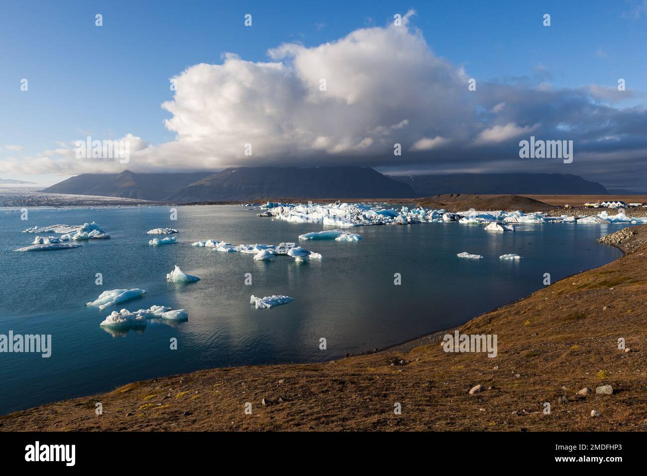 Scattered melting icebergs near Jokulsarlon glacier lagoon shore ...