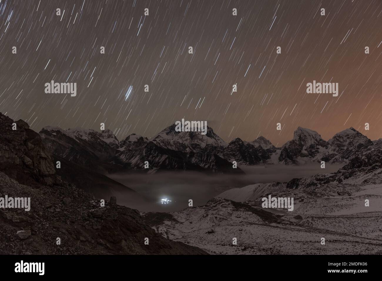 Stars falling above Himalayan mountain range lit up by a bright ...