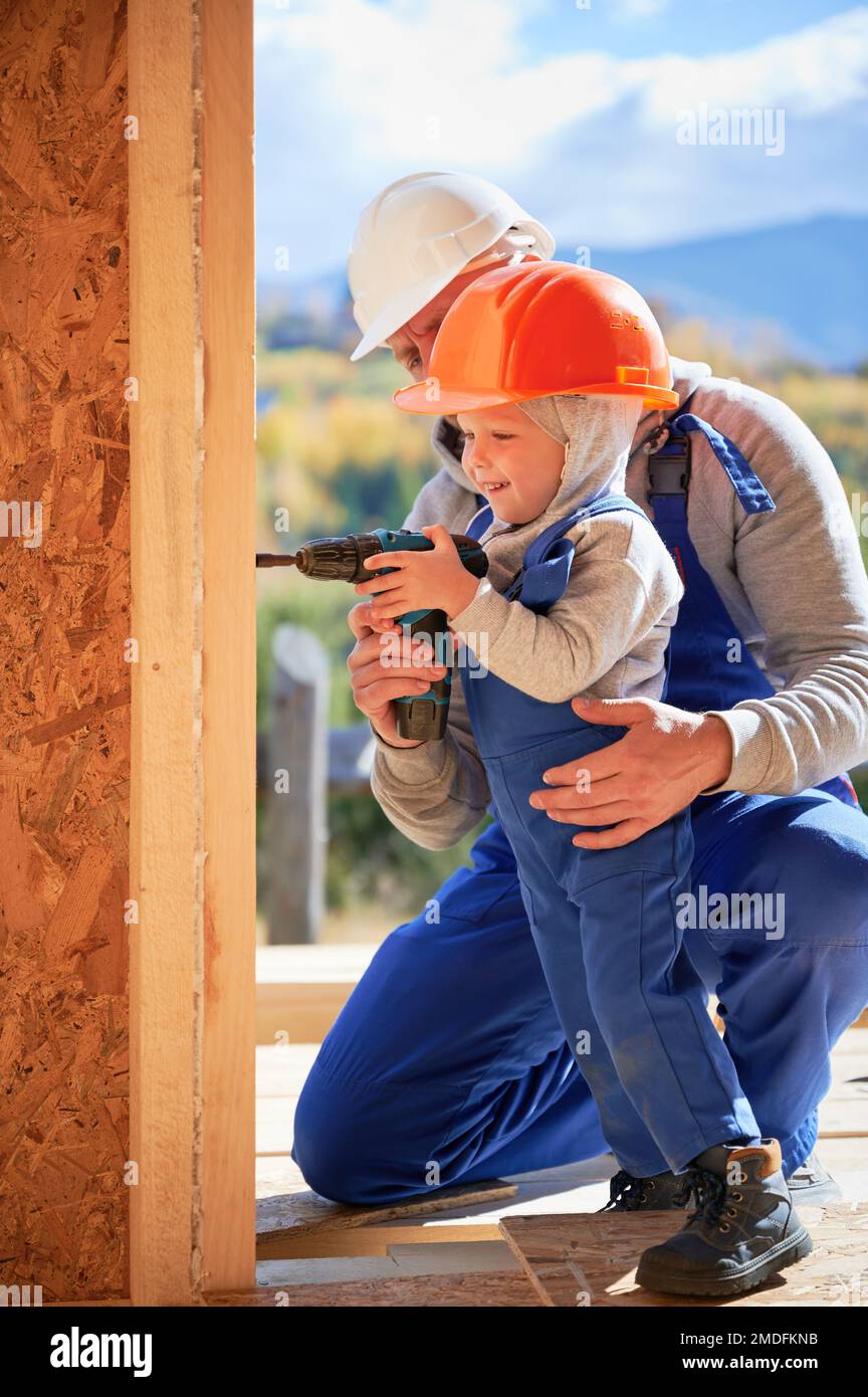 Father with toddler son building wooden frame house. Male builder and ...
