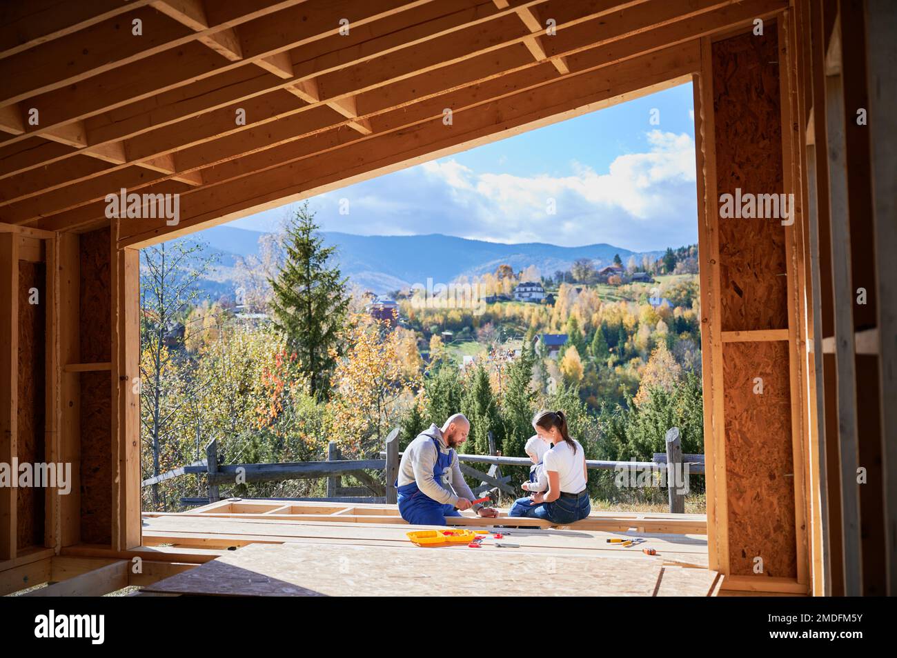 Father, mother and son building wooden frame house in the Scandinavian ...