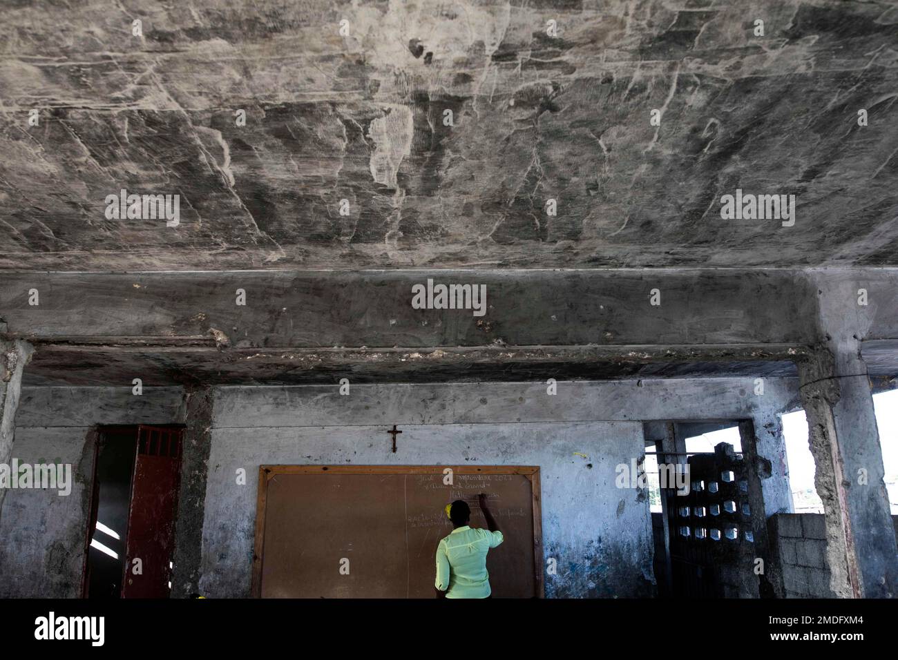 A teacher writes on a blackboard during a class at Sante Bernadette ...