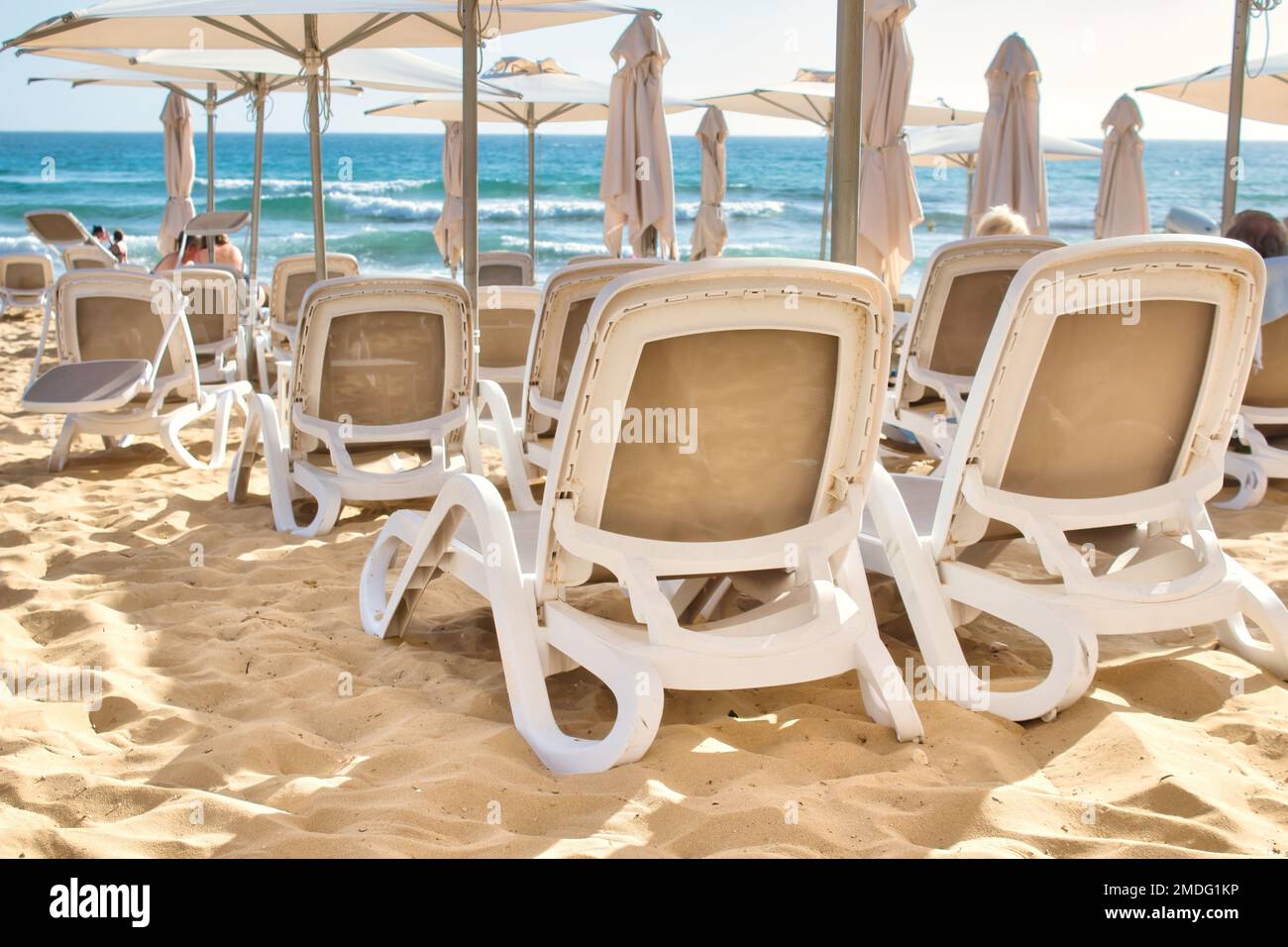 Rows of plastic beach recliners on the sandy beach at a seaside hotel ...
