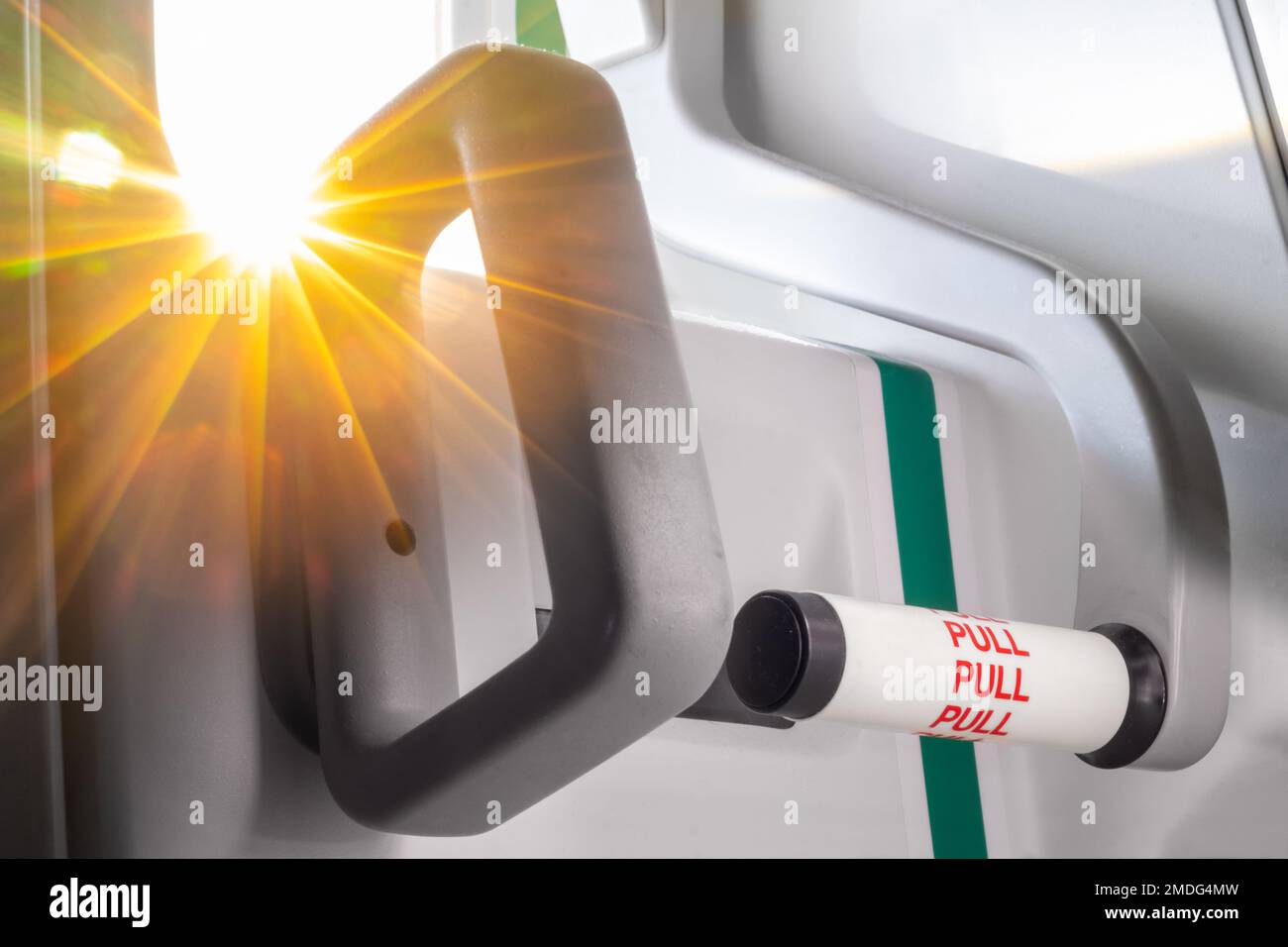Emergency exit door handle in flying airplane with sun rays from small ...