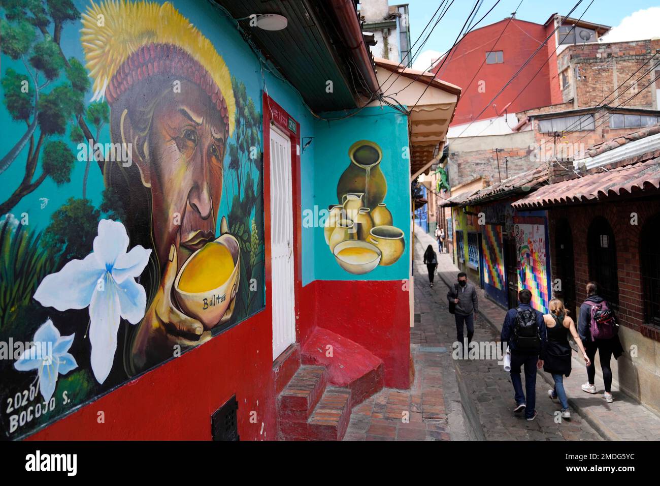 A mural of an Indigenous man sipping chicha decorates a facade in La ...