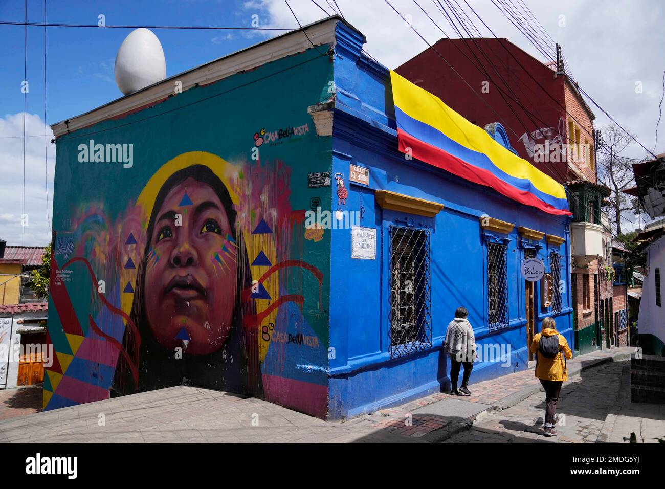 Pedestrians walk near a mural of an Indigenous woman painted by street ...