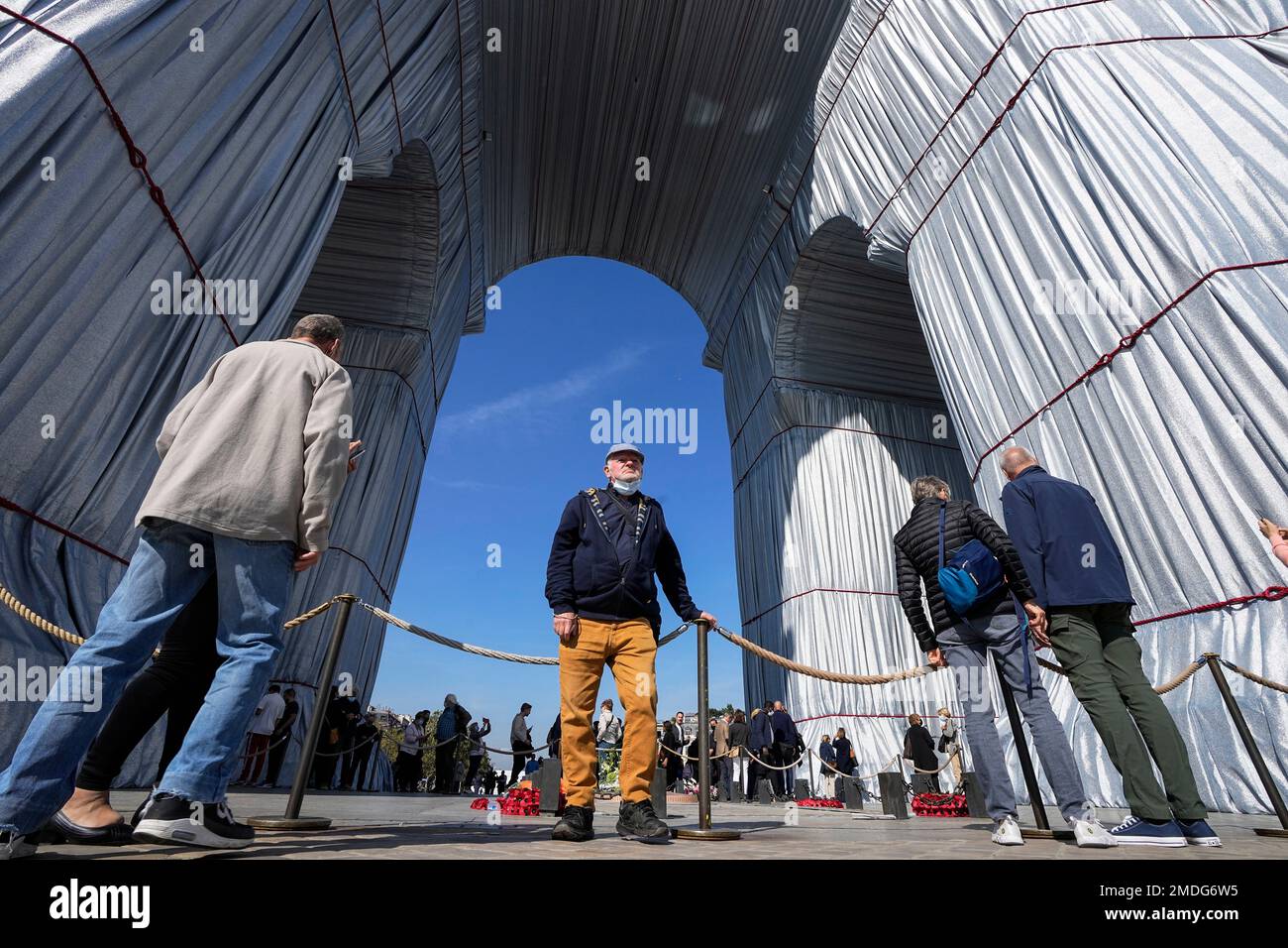 A man poses for a picture under the wrapped Arc de Triomphe monument in ...