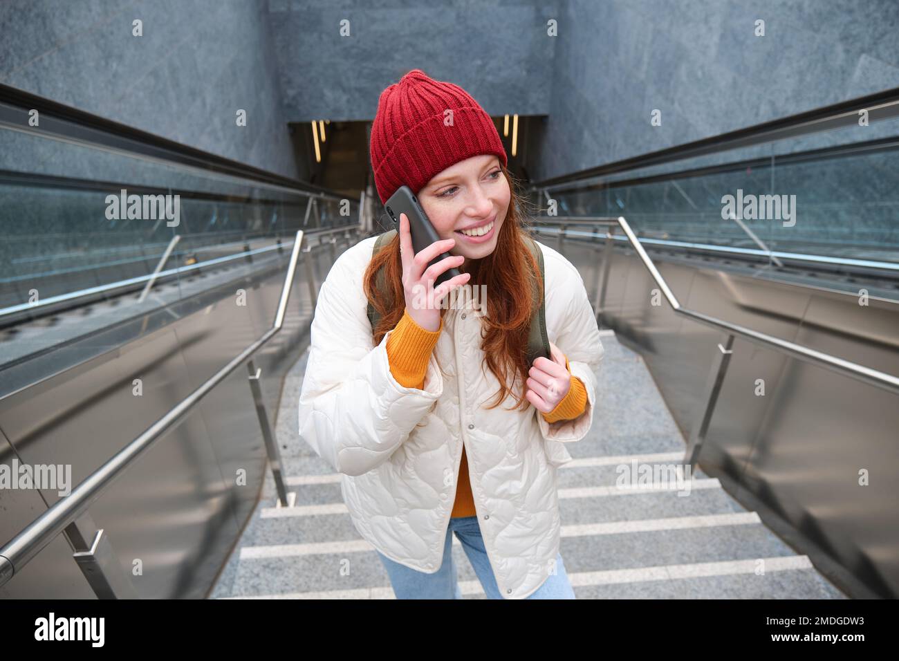 Portrait of young redhead woman walks around city, goes up stairs with ...