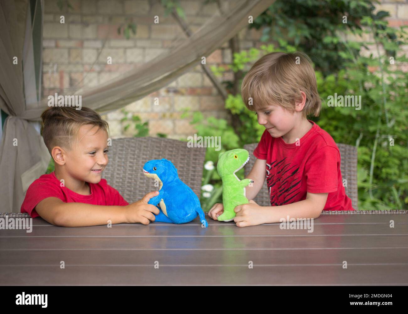 Two boys play at table with plush dinosaurs in role-playing games ...