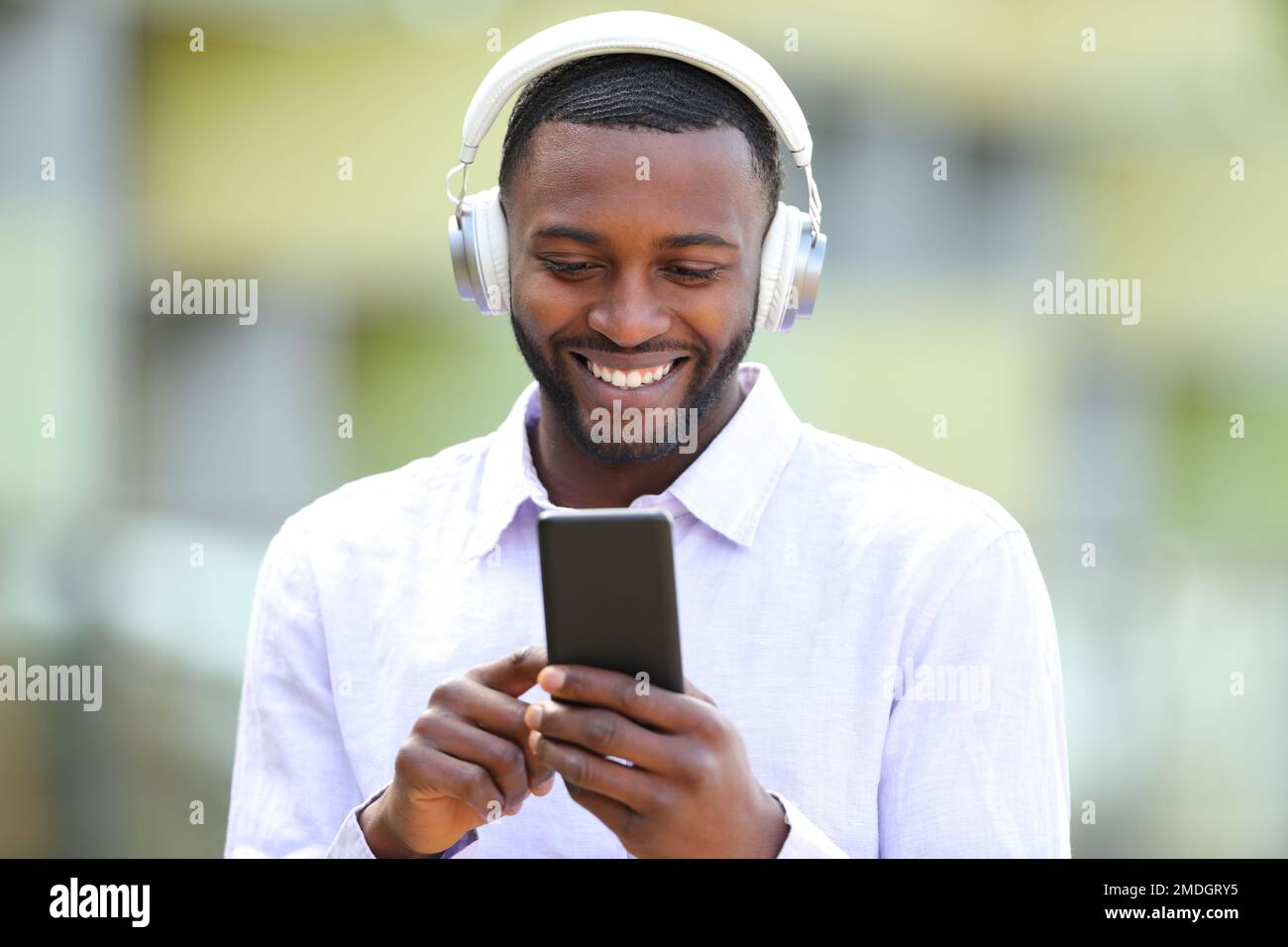 Front view portrait of a happy black man wearing wireless headphones ...