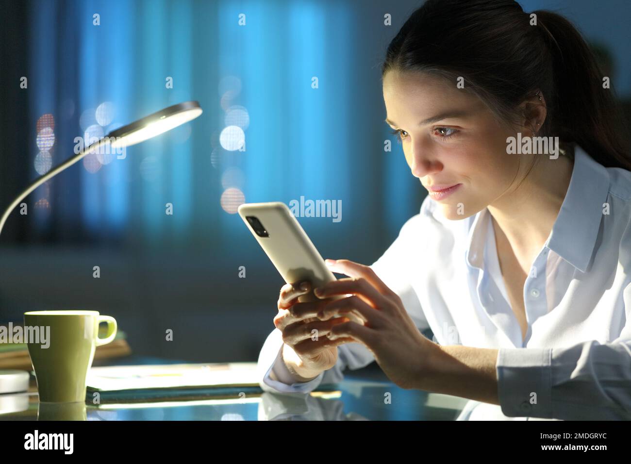 Entrepreneur in the night checking cell phone in a desk Stock Photo - Alamy