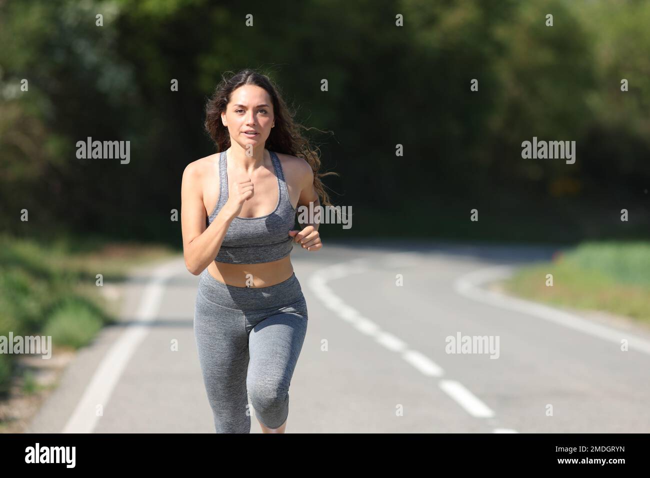 Front view portrait of a woman running in a road Stock Photo - Alamy