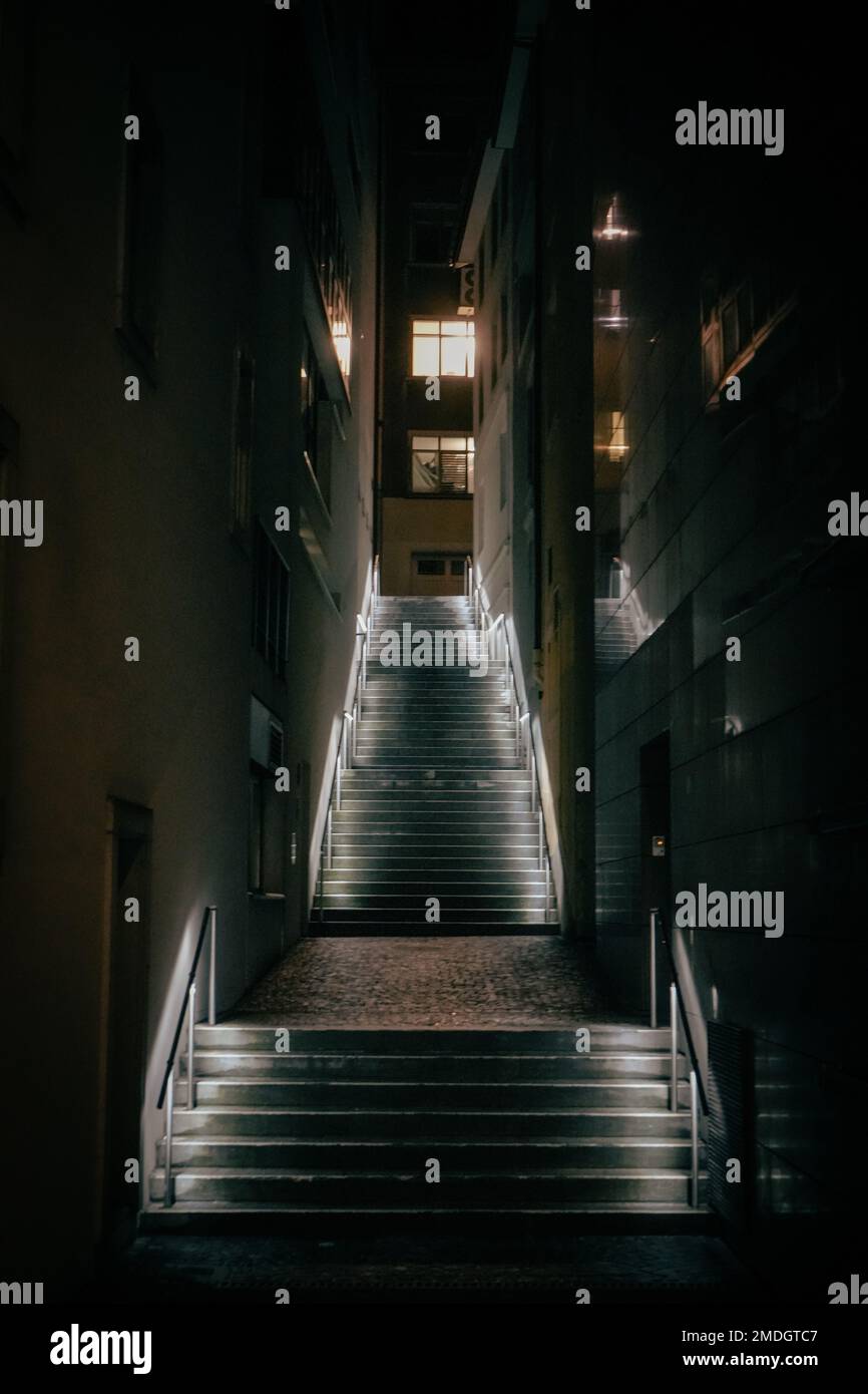 A vertical shot of cascading city stairs in a narrow alley with night ...