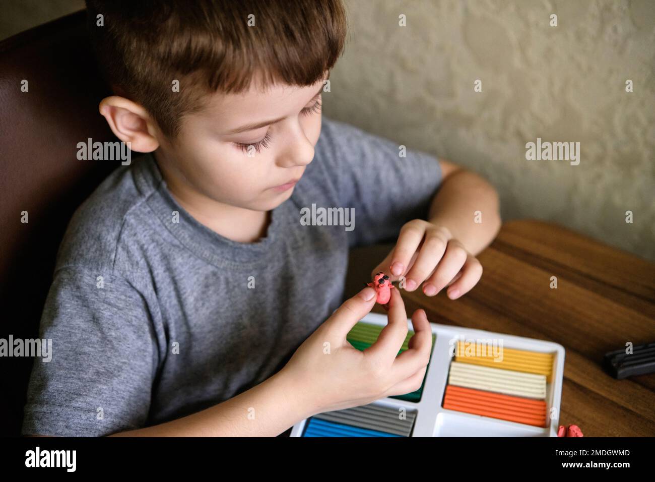 Elementary school age Caucasian child boy plays with plasticine on ...