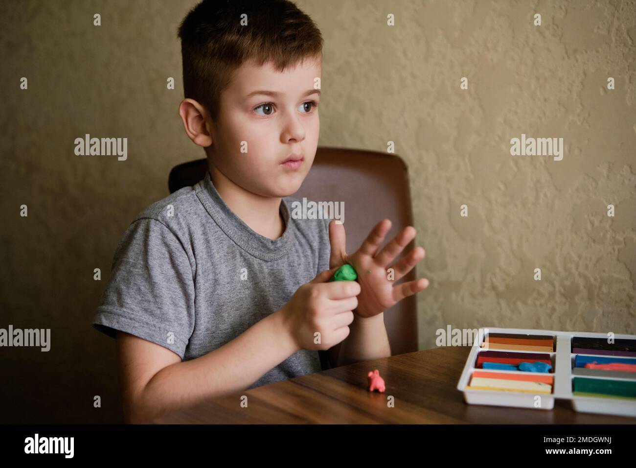Elementary school age Caucasian child boy plays with plasticine on ...