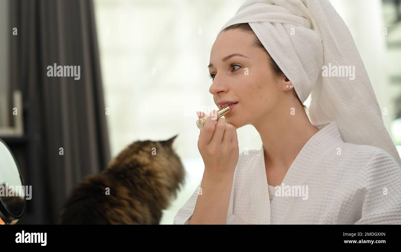 Beautiful caucasian woman with natural makeup applying lip balm front ...