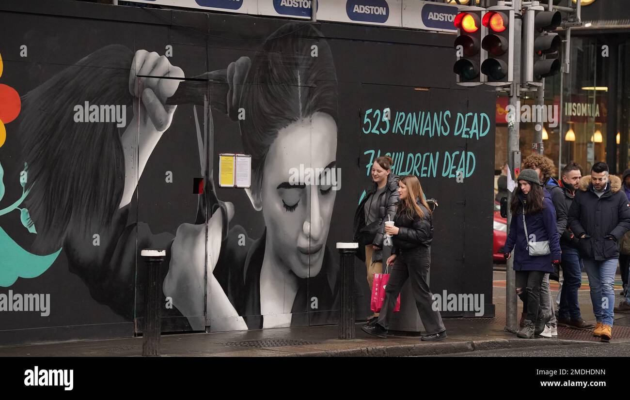 People walk past a mural highlighting the plight of women in Iran, on ...
