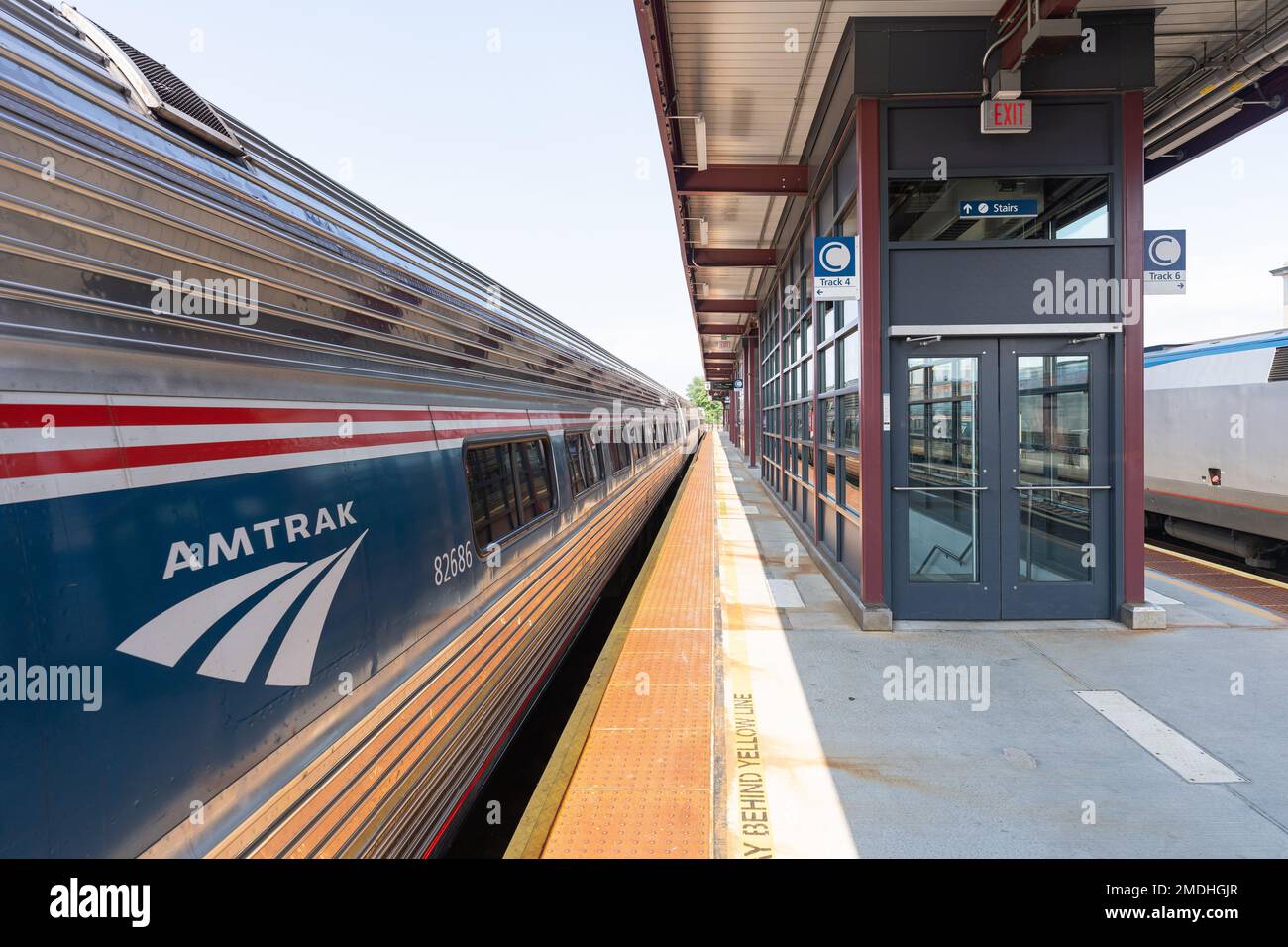 A wide angle photo of an Amtrak Train stopped at a station as viewed from the elevated platform ...