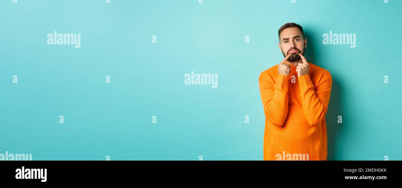 Image of gloomy bearded man, making sad face and frowning, standing ...