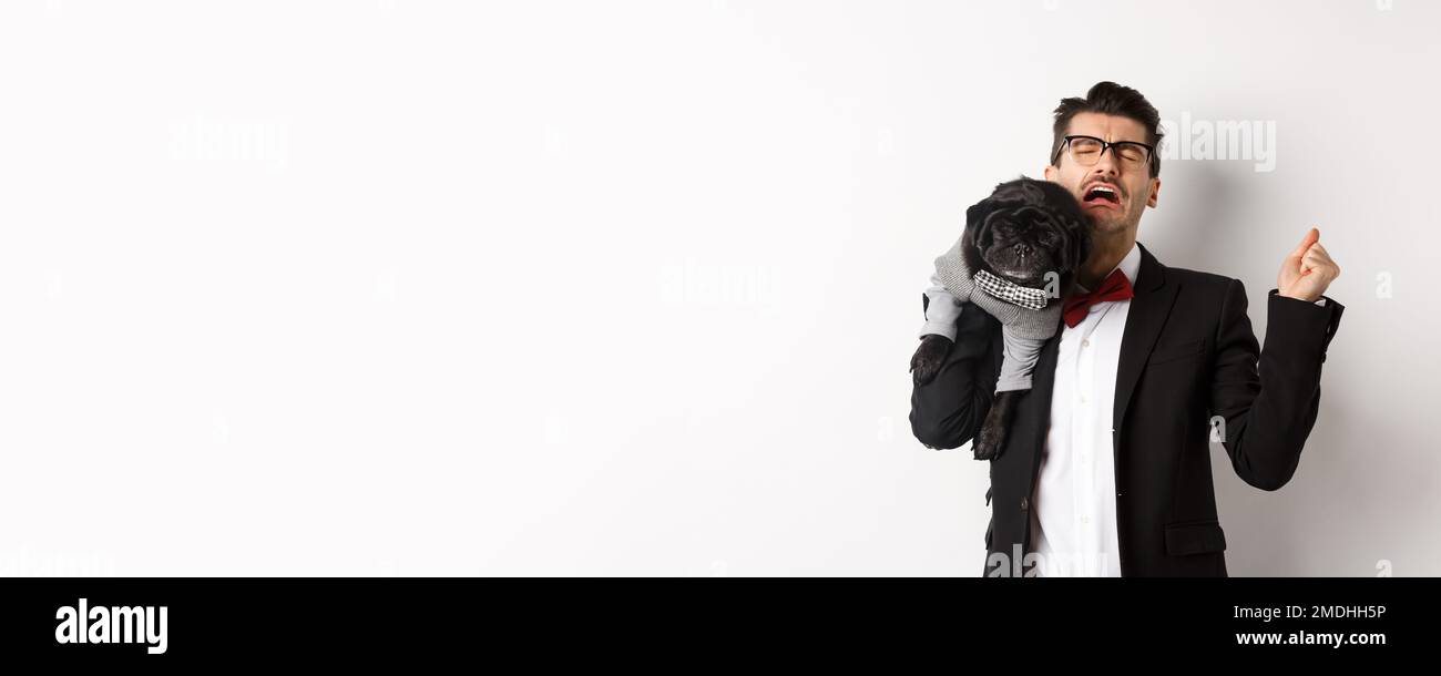 Sad man in suit, holding cute small dog on shoulder and crying with ...