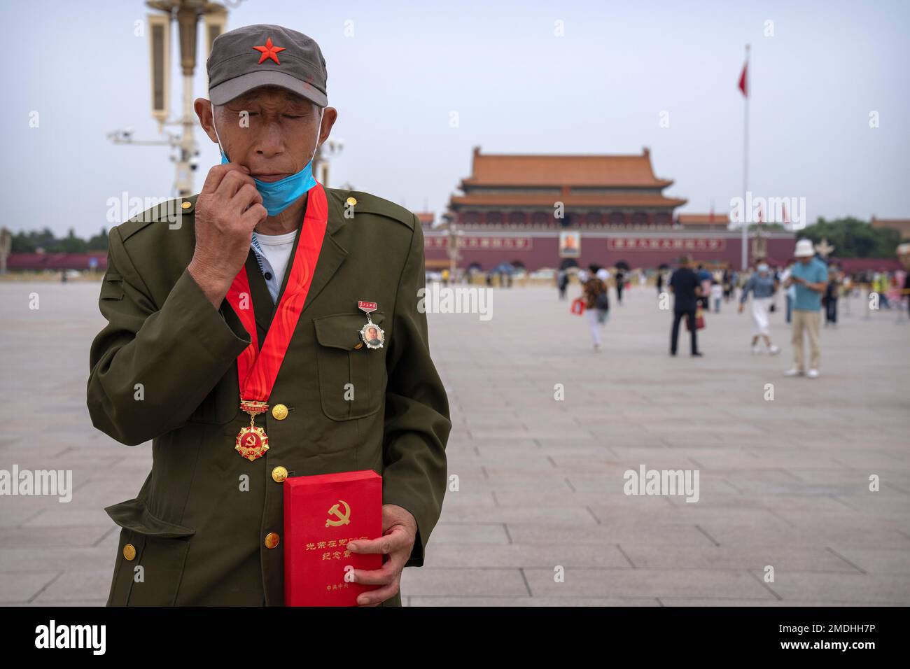 A Chinese military veteran adjusts his face mask as he poses for a ...
