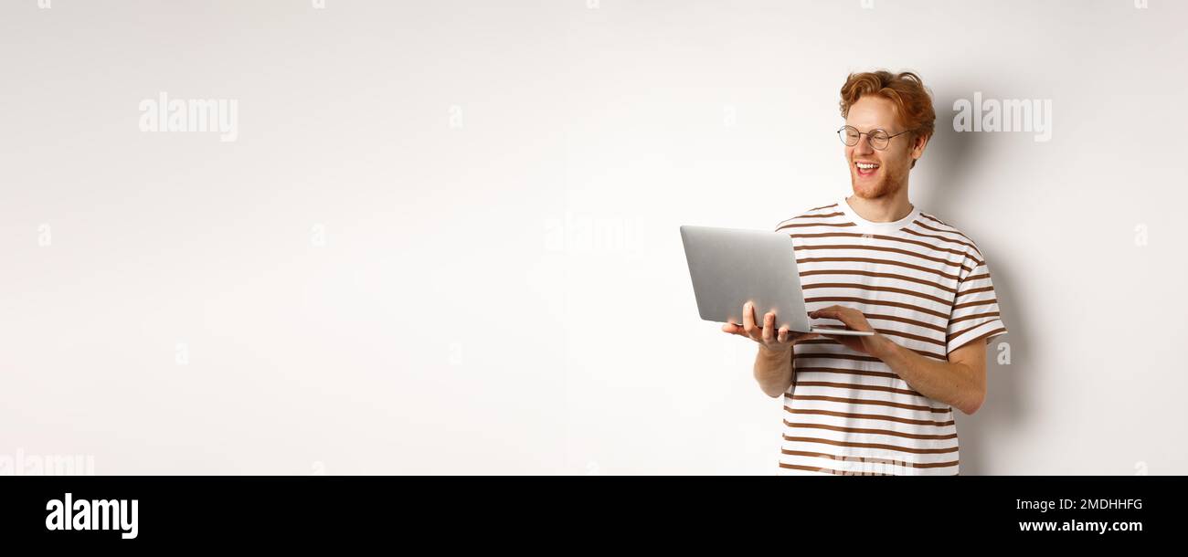 Handsome redhead man working freelance on laptop, smiling and looking ...