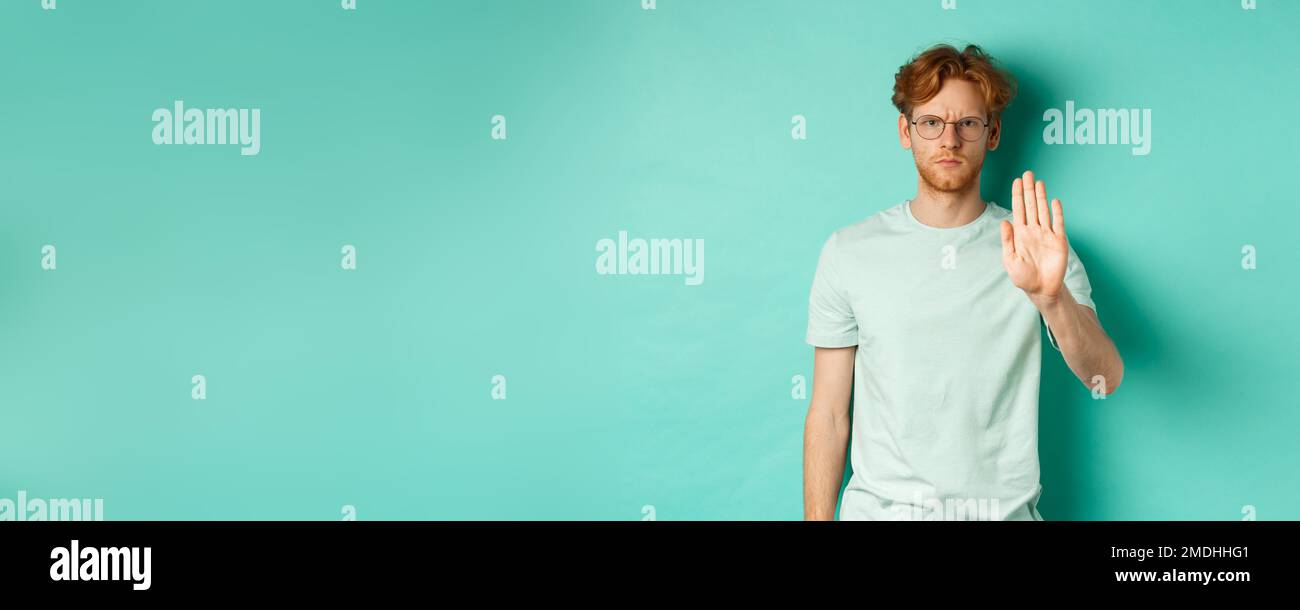 Angry and serious young man with red hair, wearing glasses, showing ...