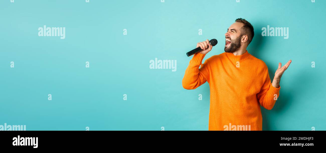 Handsome adult man perform song, singing into microphone, standing ...