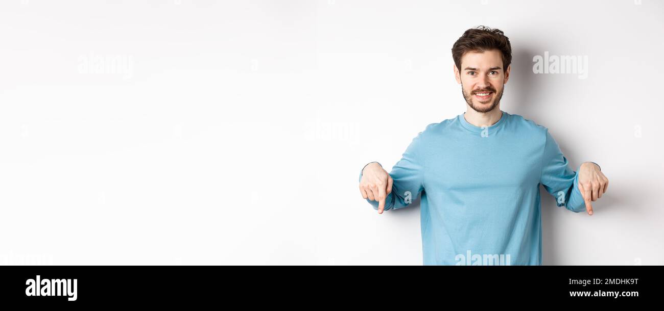 Smiling confident man pointing fingers down, showing promo banner or ...