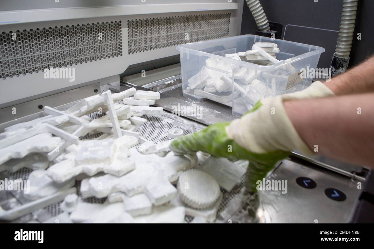 A worker putting into a box models printed on 3D printer and covered ...