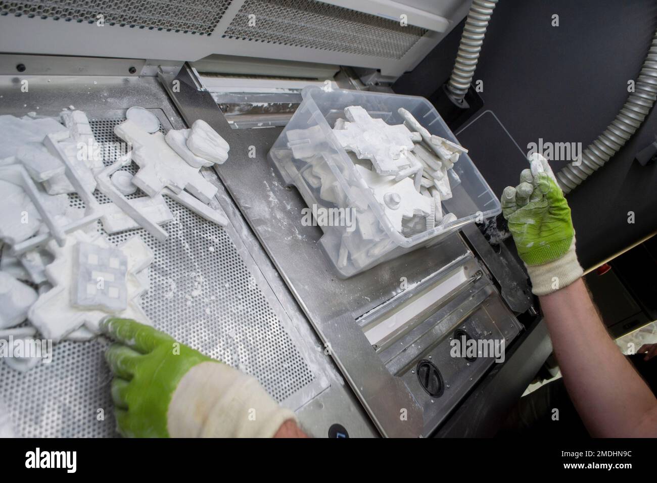 A worker putting into a box models printed on 3D printer and covered ...
