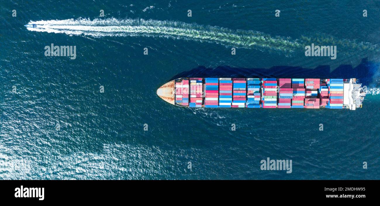 Pilot boat running near cargo maritime ship with contrail in the ocean ...