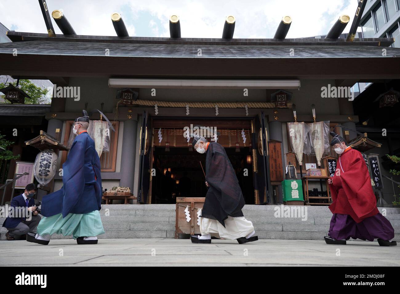 Shinto priests in ritual clothing perform a ceremonial rite for an ...