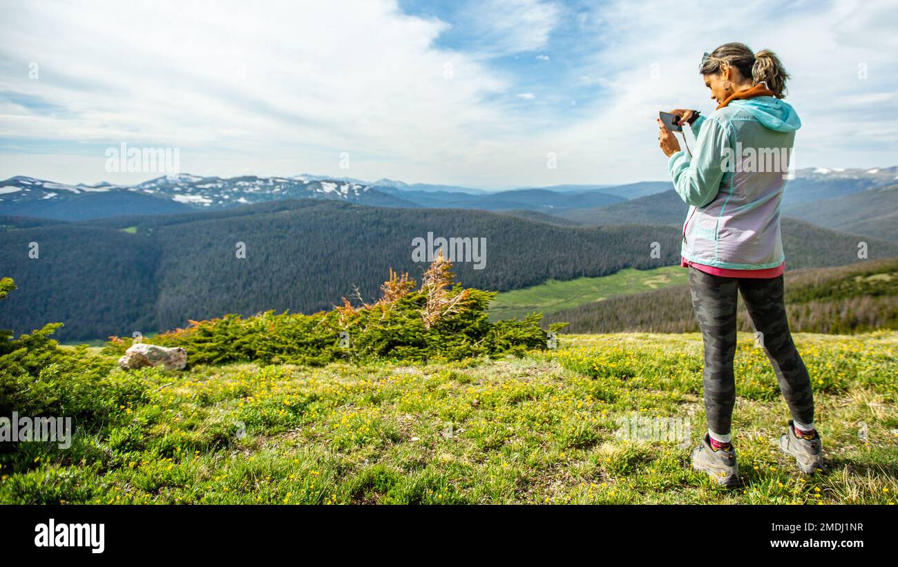 Hiker photographs the landscape, Rocky Mountain National Park is an ...