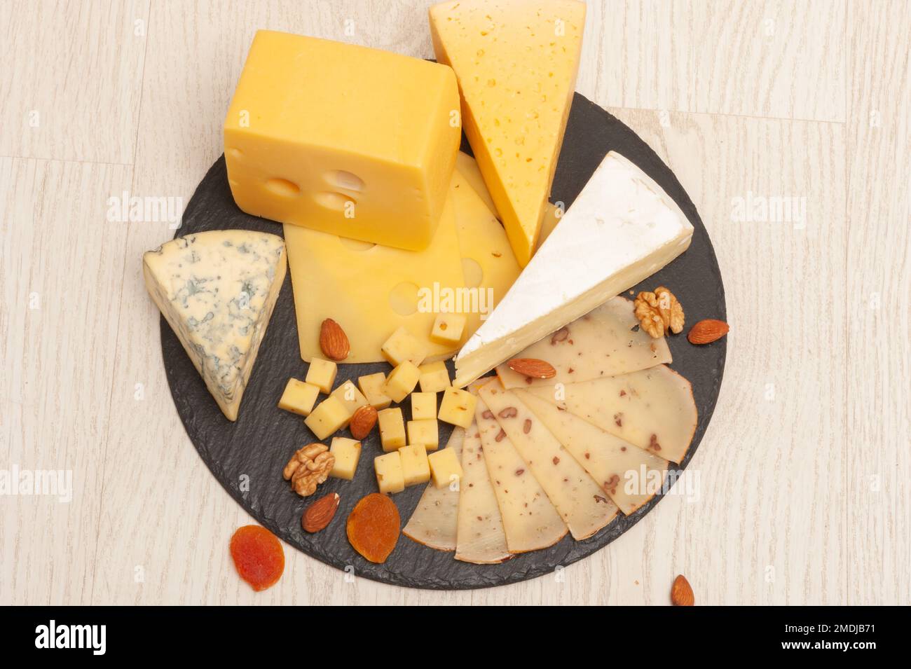 Different types of cheese on a black graphite board decorated with ...