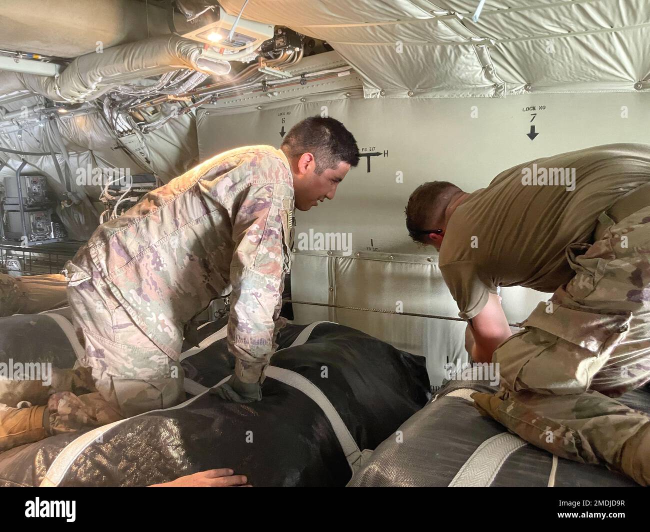 SPC Loyola and SPC Johnston attach parachute static lines from the low ...