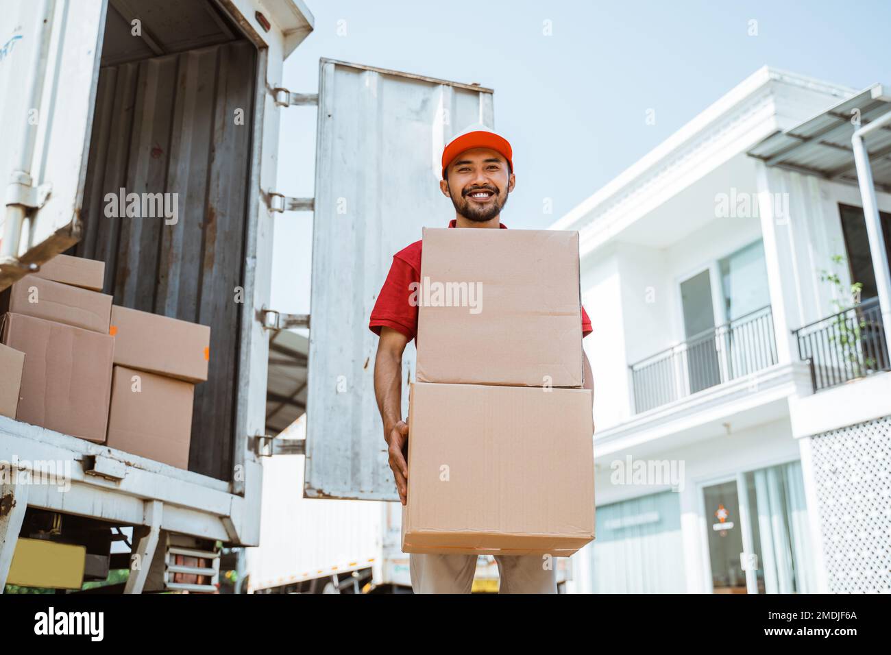 delivery man smiling while carrying boxes to customers from containers ...