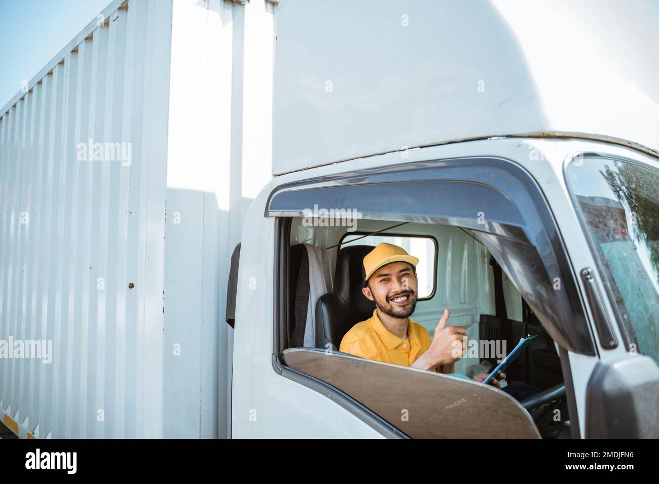 delivery man in yellow uniform with thumbs up while driving Stock Photo ...
