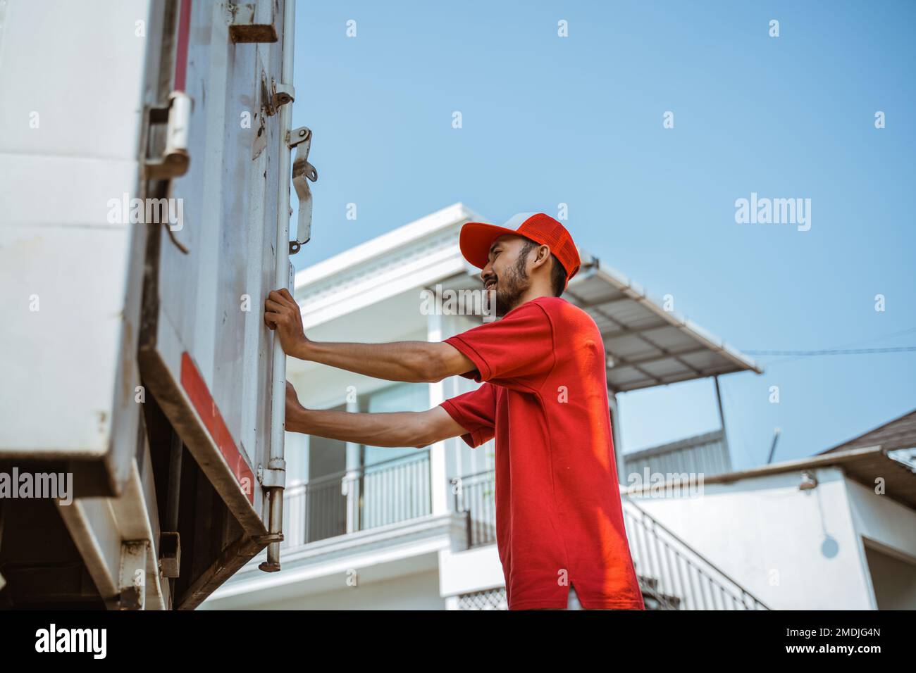 delivery man in red closing goods delivery truck container doors Stock ...