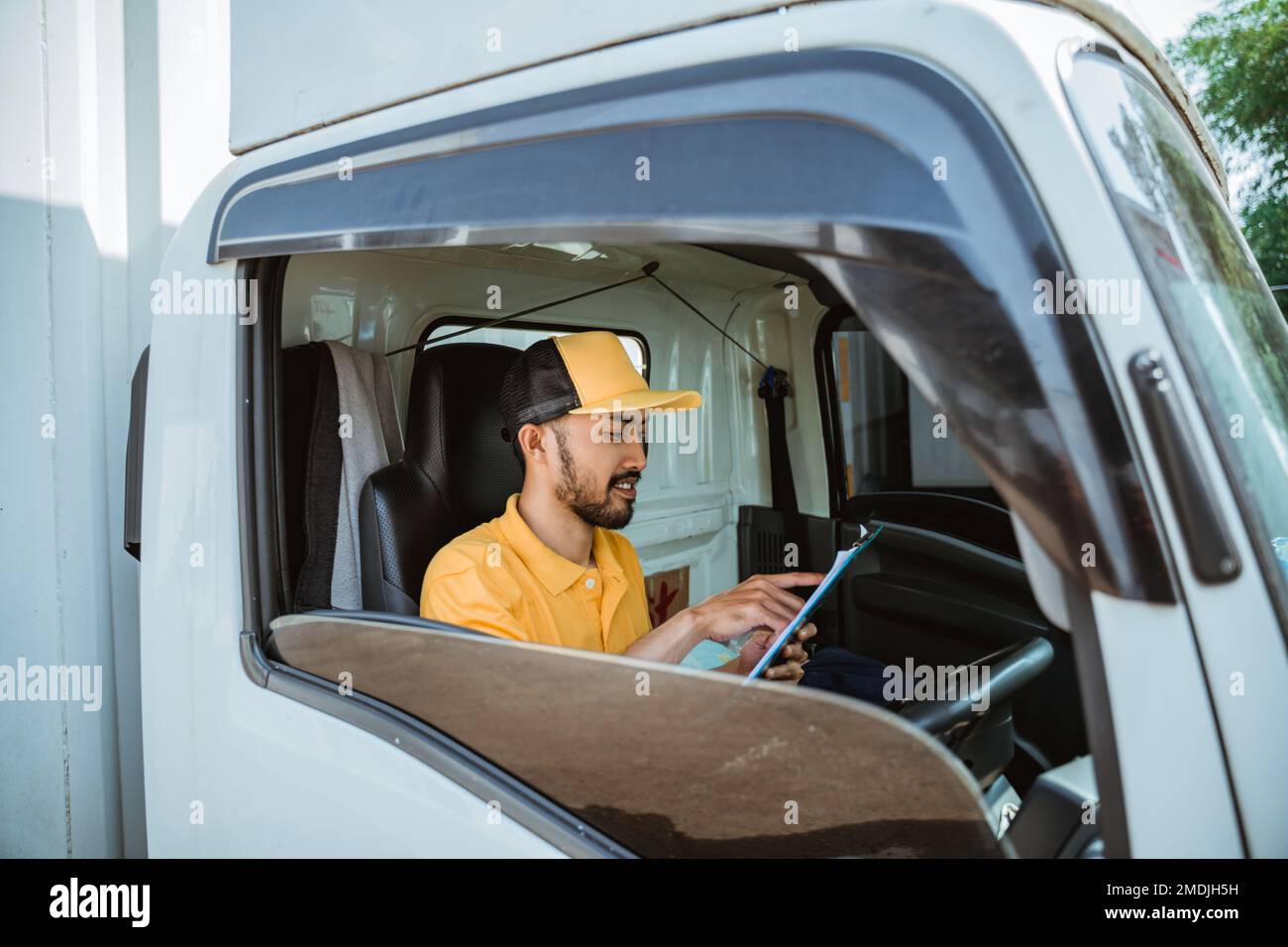 male driver in yellow uniform checks checklist on clipboard Stock Photo ...