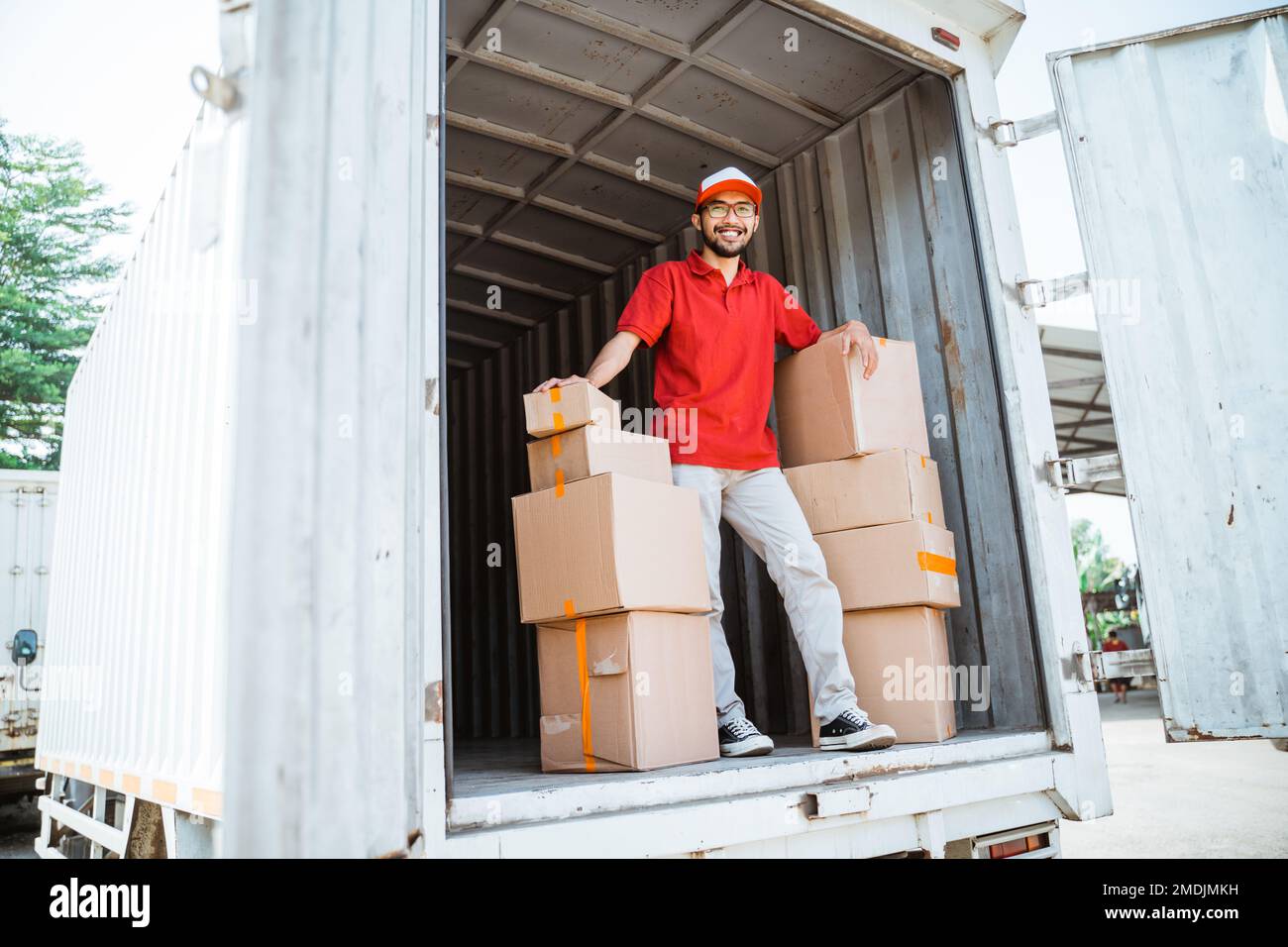 delivery man standing between several package boxes in container truck ...