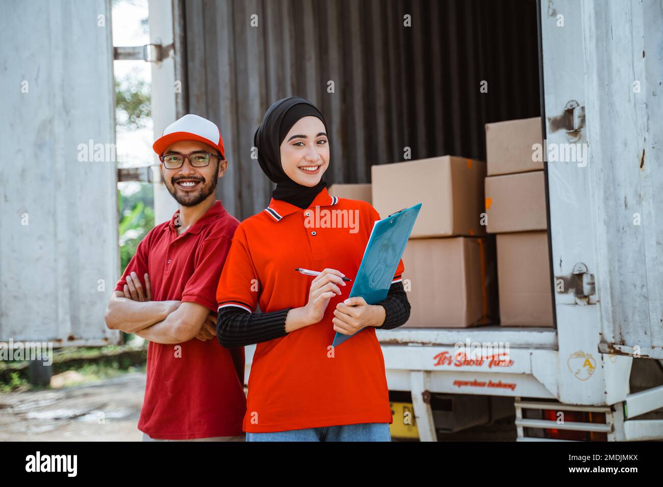 two employees in red uniforms standing behind the logistics container ...