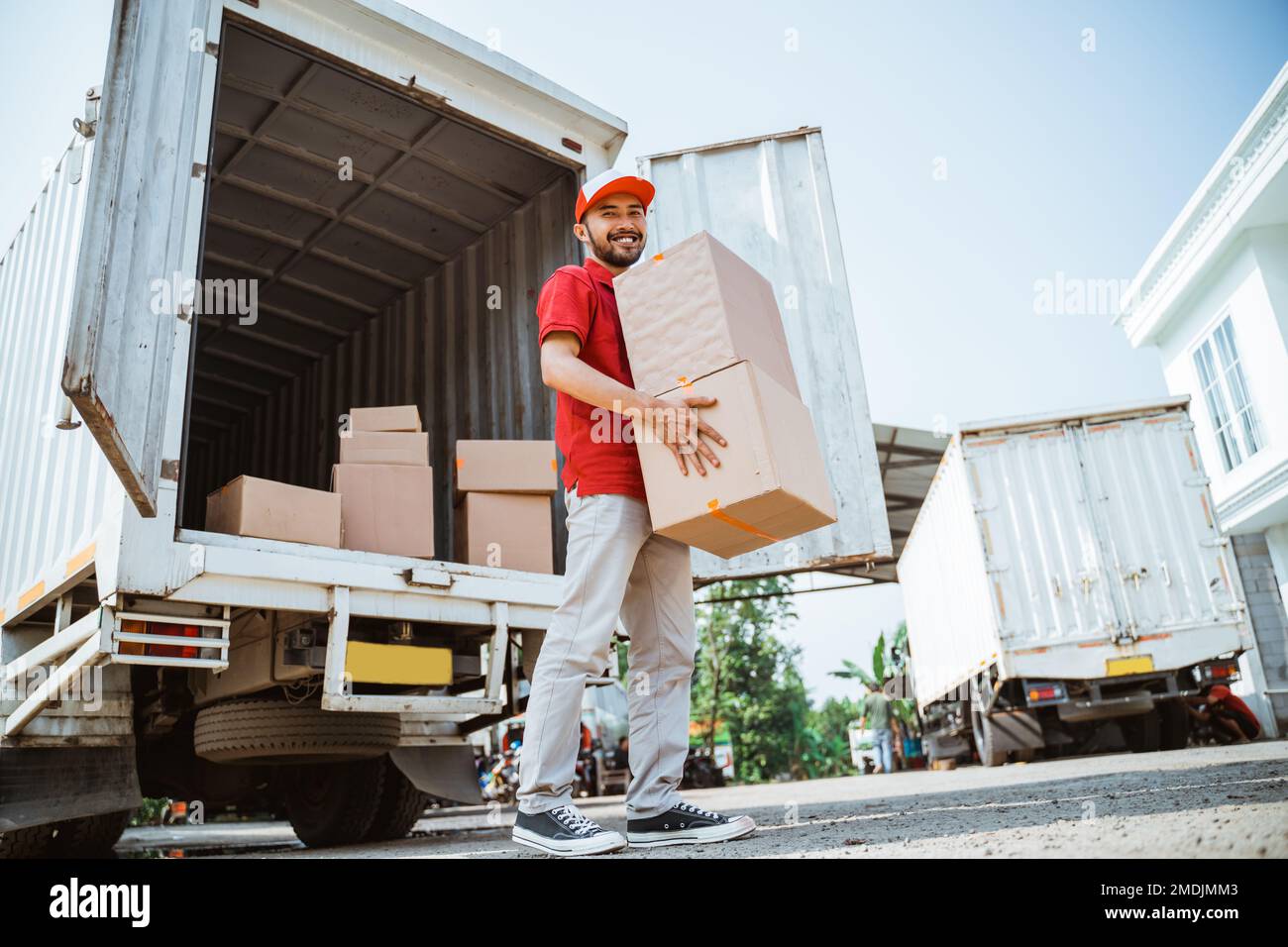 delivery man in red uniform smiling while lifting packages box Stock ...