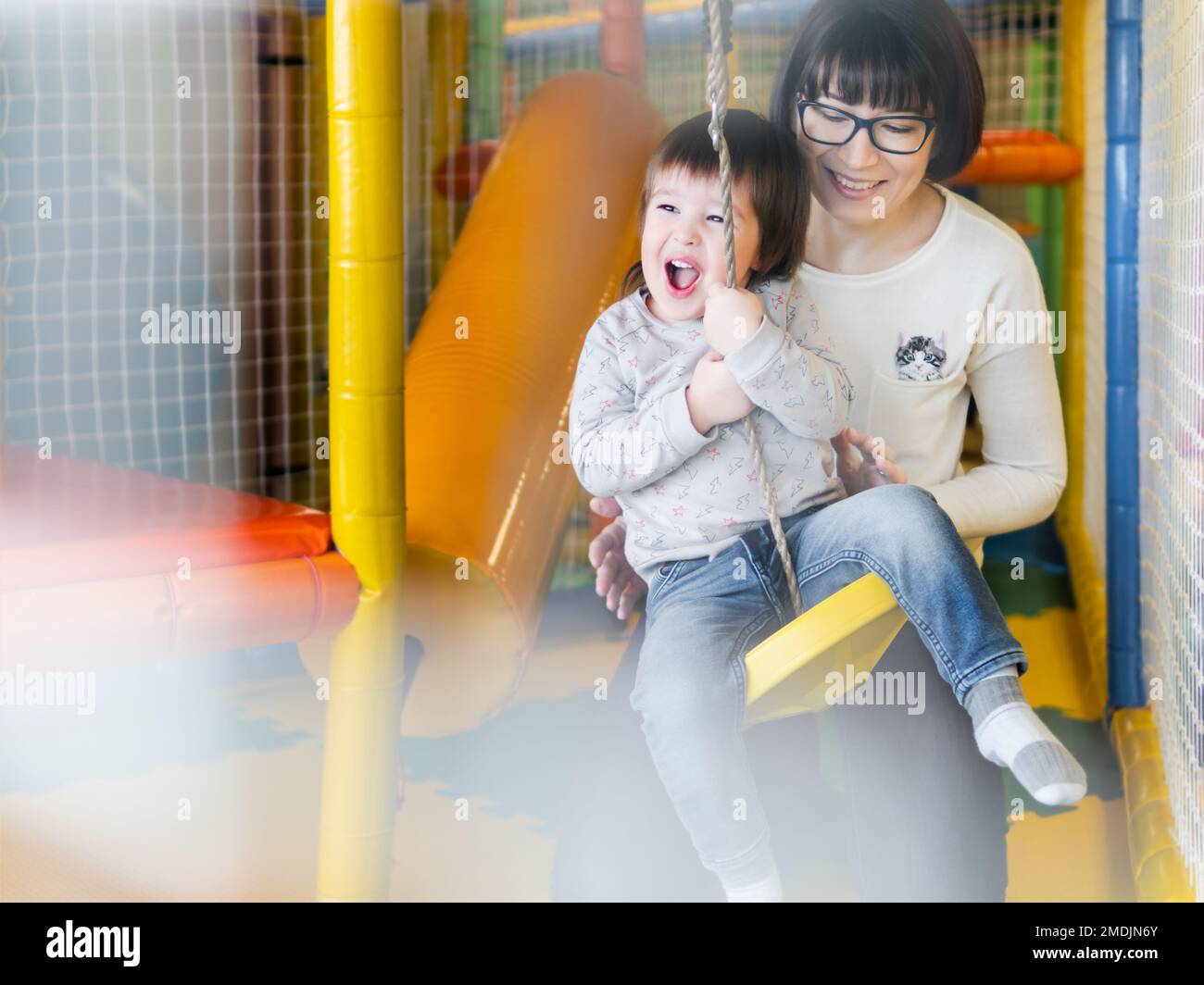 Toddler plays on rope swing with his mother or babysitter. Physical ...