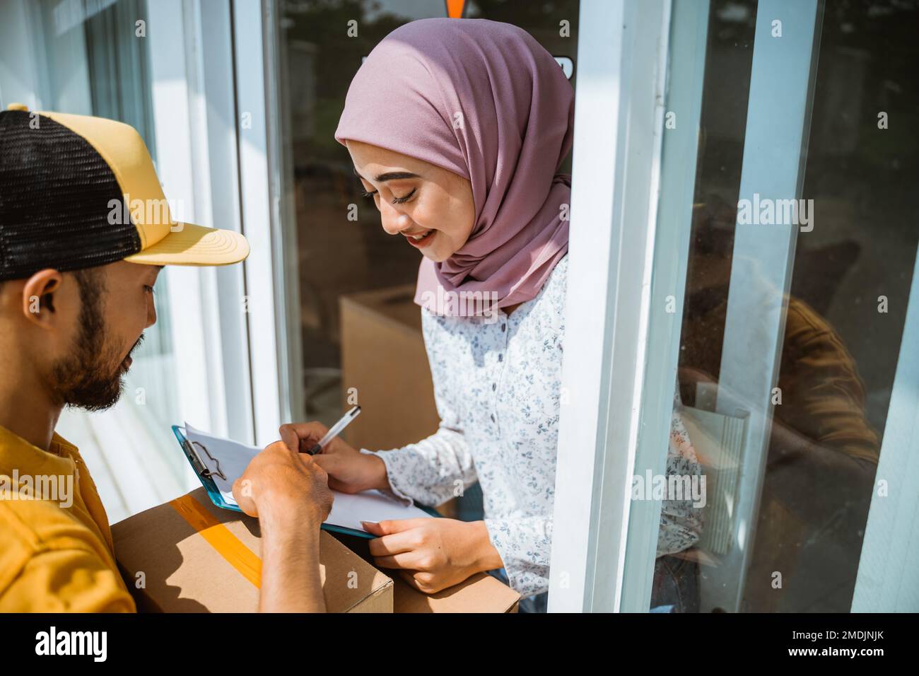 female customer in veil signs while receiving from delivery men Stock ...