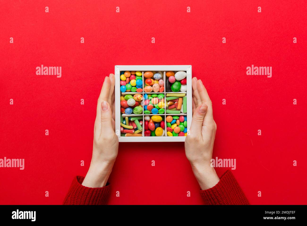 Female hands with delicious candies in box on color background Stock ...