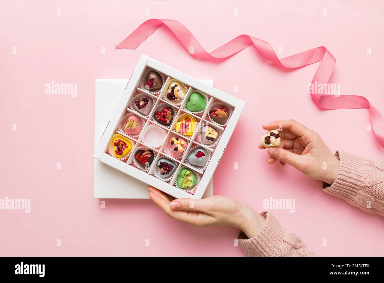 Female hands with delicious candies in box on color background Stock ...