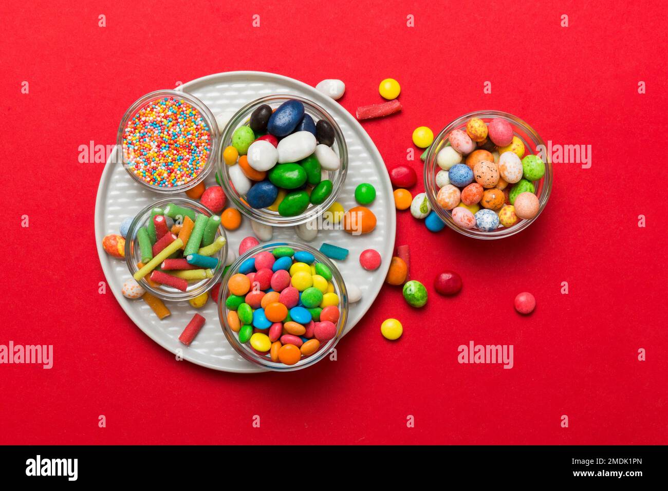 different colored round candy in bowl and jars. Top view of large ...