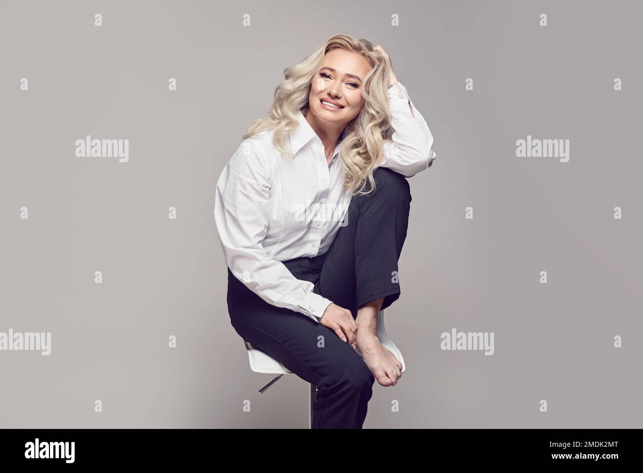 Happy maturity. Charming mature woman sincerely smiling on a gray ...