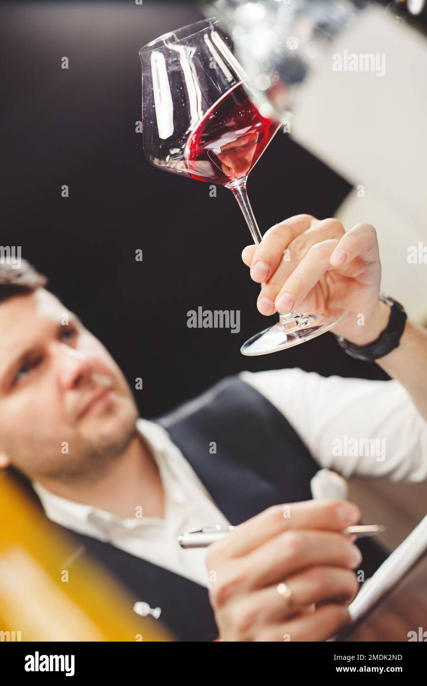 Skilled male sommelier looks carefully at drink in stem glass Stock ...