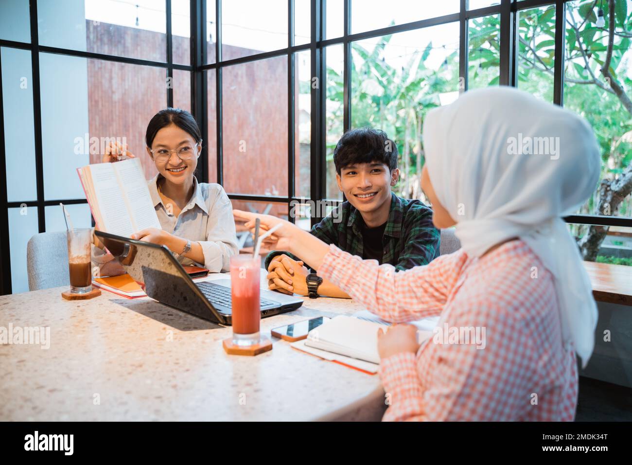 group of friends using a laptop and books doing homework Stock Photo ...